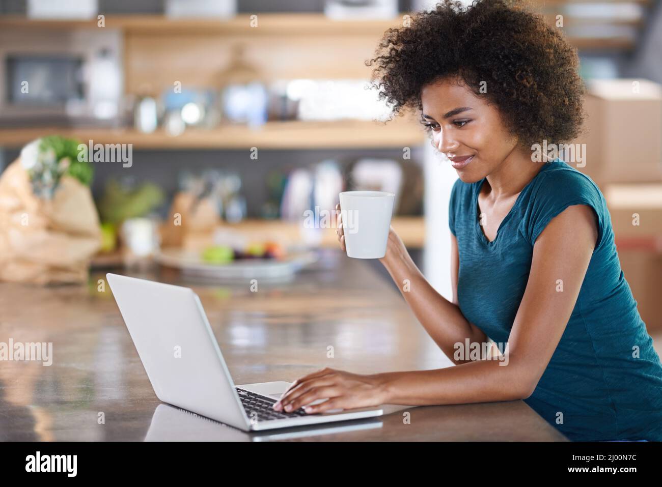 Having coffee with a friend. Young woman using a laptop while drinking ...