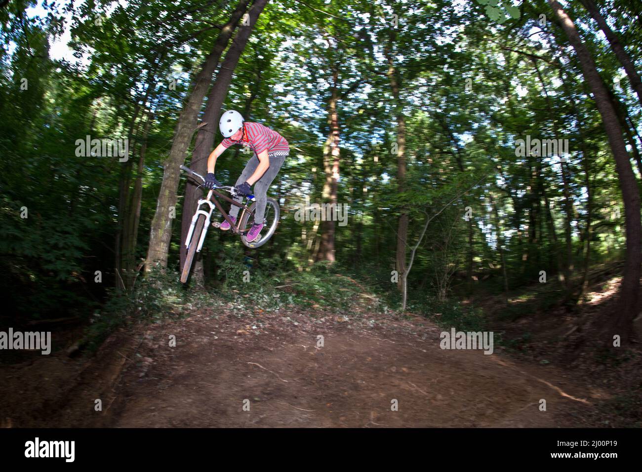 cute teen jumping with his bike over a natural ramp in the forest Stock ...