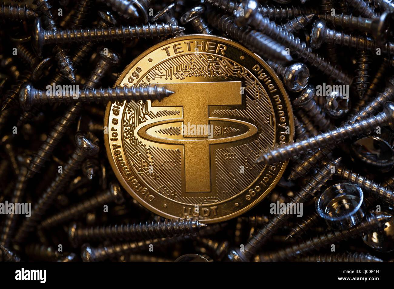 TETHER USDT cryptocurrency physical coin placed between metal screws ...