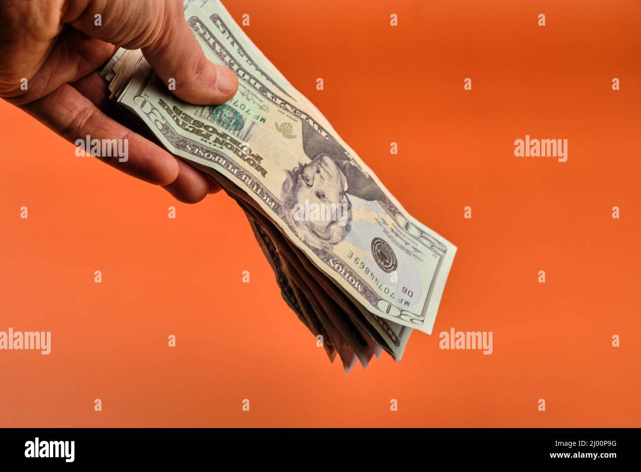 Man's hand with a bunch of dollar bills on an orange background Stock ...