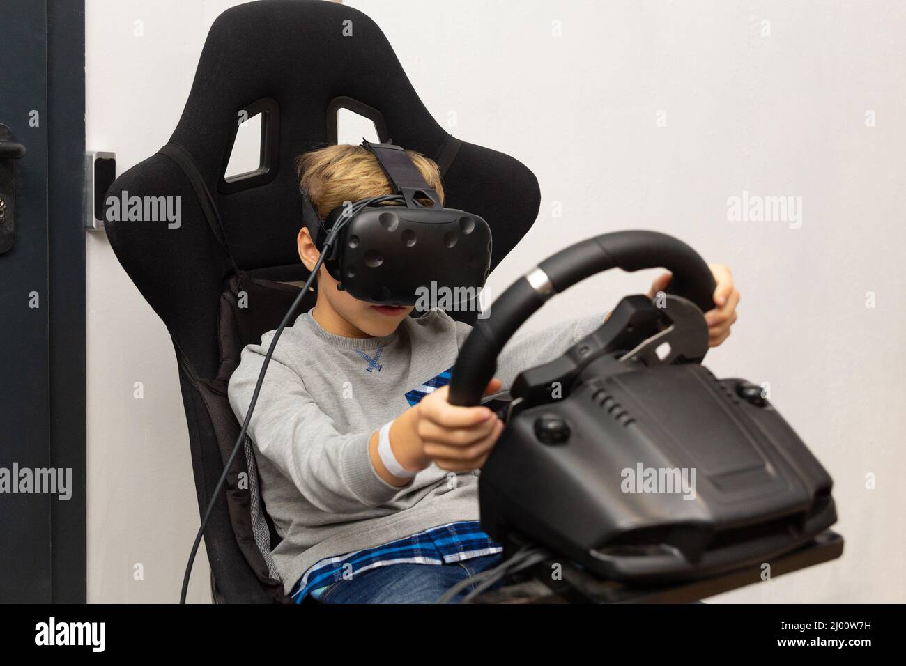 The boy plays on the racing simulator in glasses of a virtual reality ...