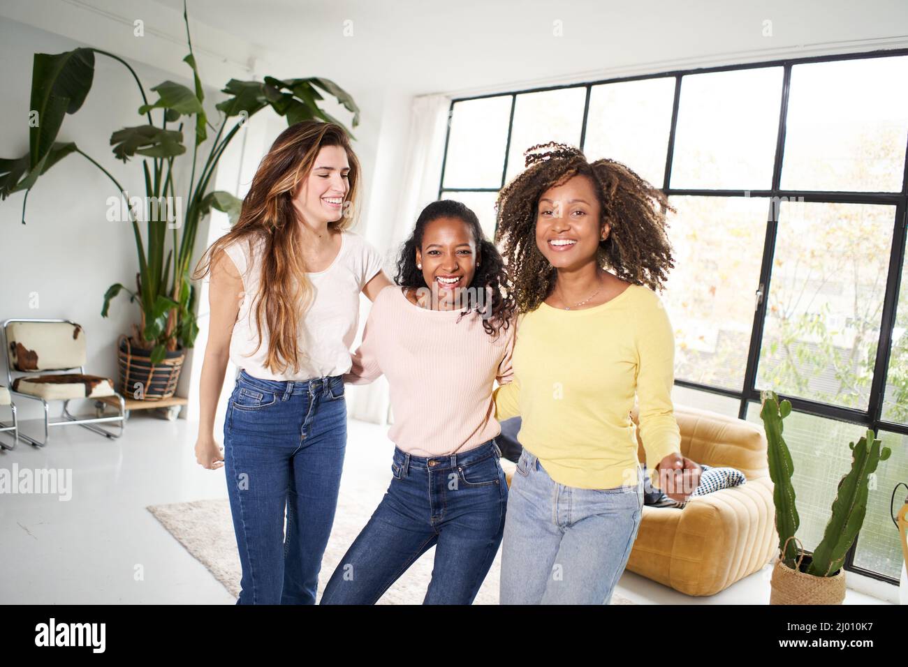 Three funny multi cultural female friends dancing living room indoors ...