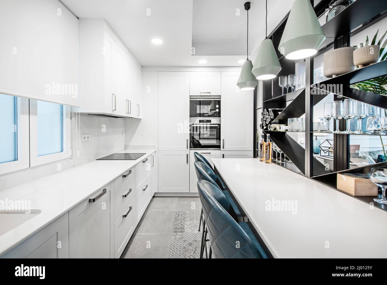 Kitchen with white wooden furniture, oven column and microwave next to ...