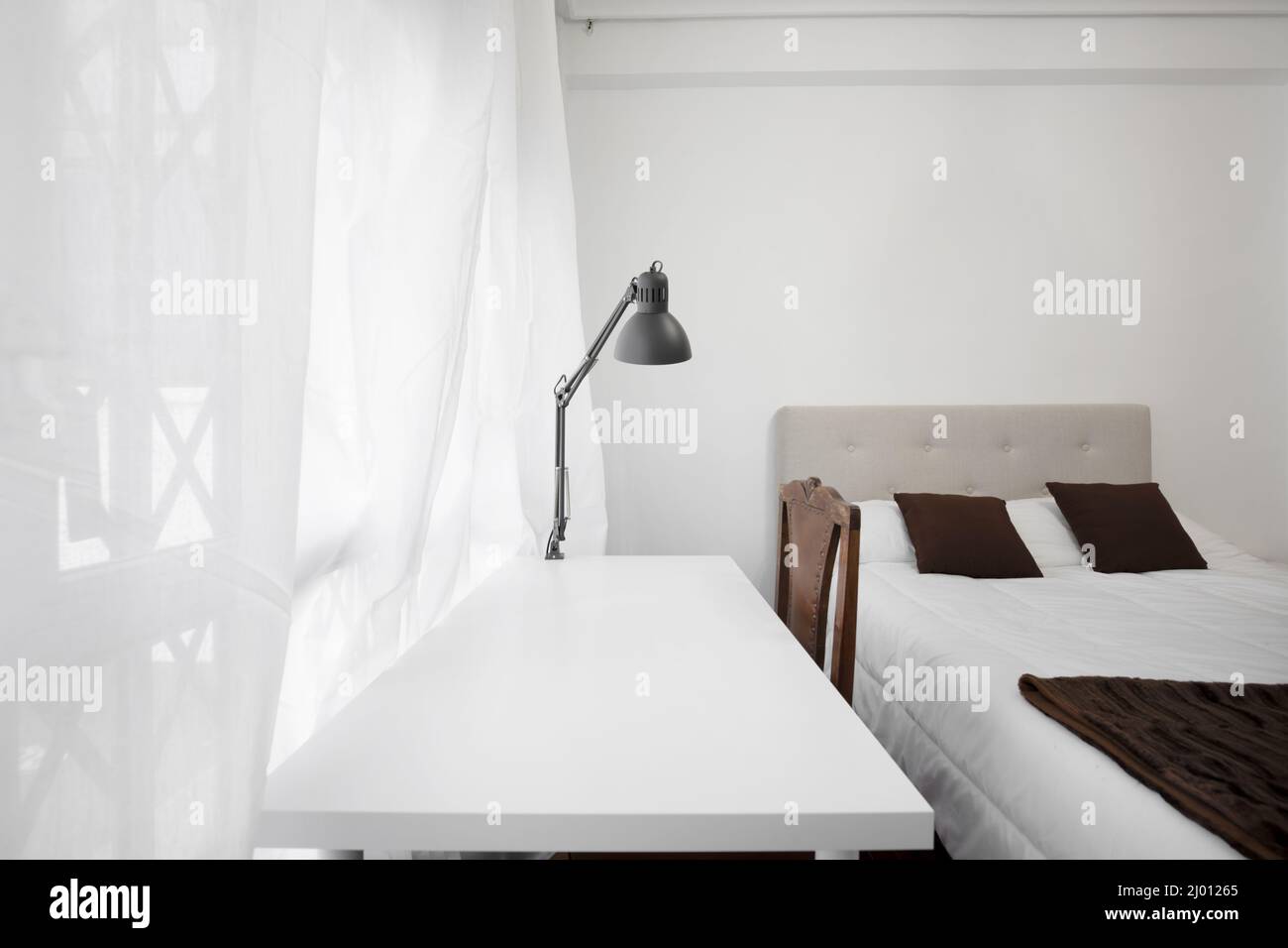 White study table with black lamp next to the window with white ...