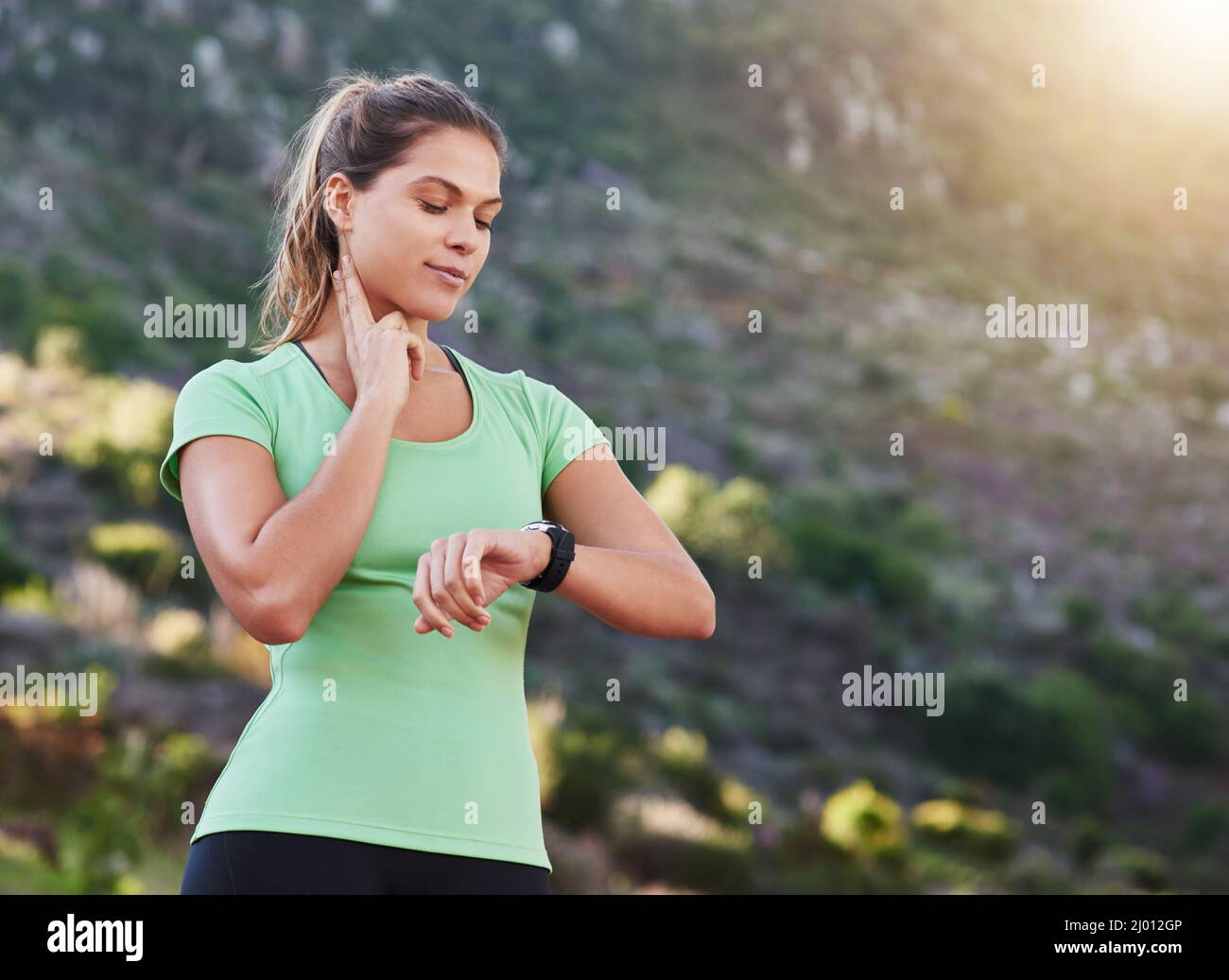 Getting more fit by the day. Shot of a young woman checking her heart ...
