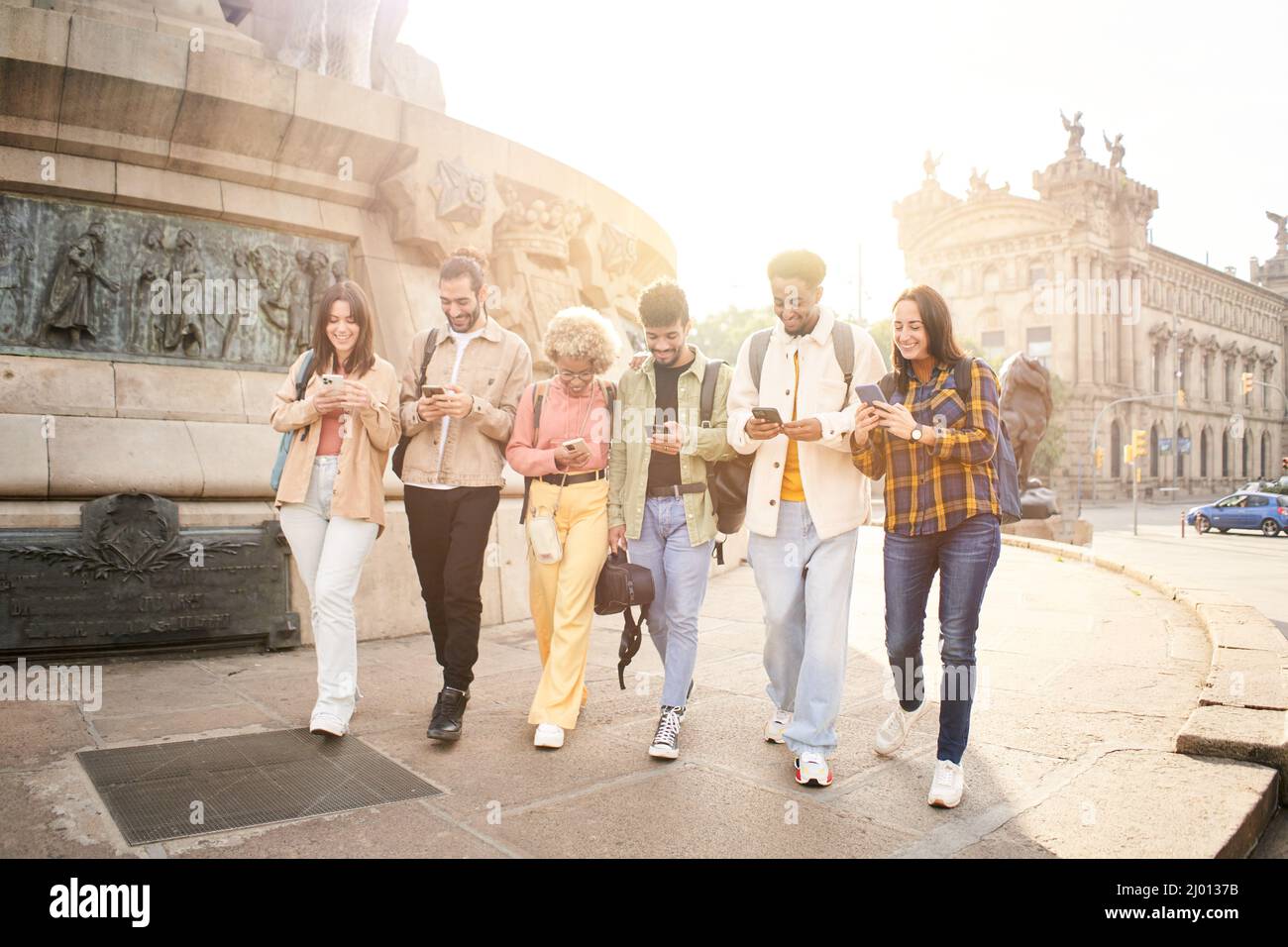 Group of happy young people using phones outdoors while walking and ...