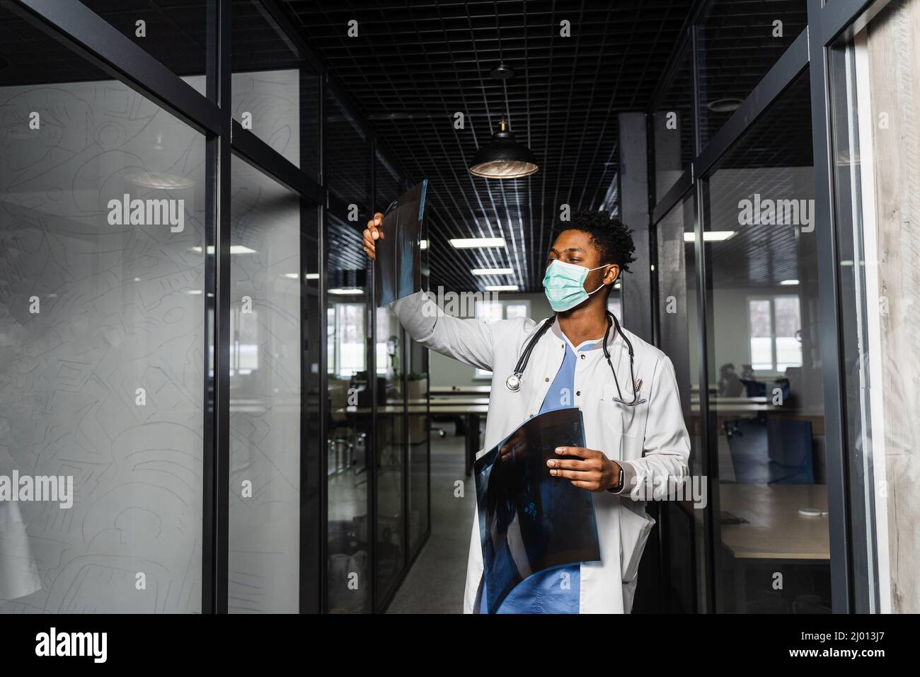 African doctor examines x-rays in a medical clinic. Black student in ...