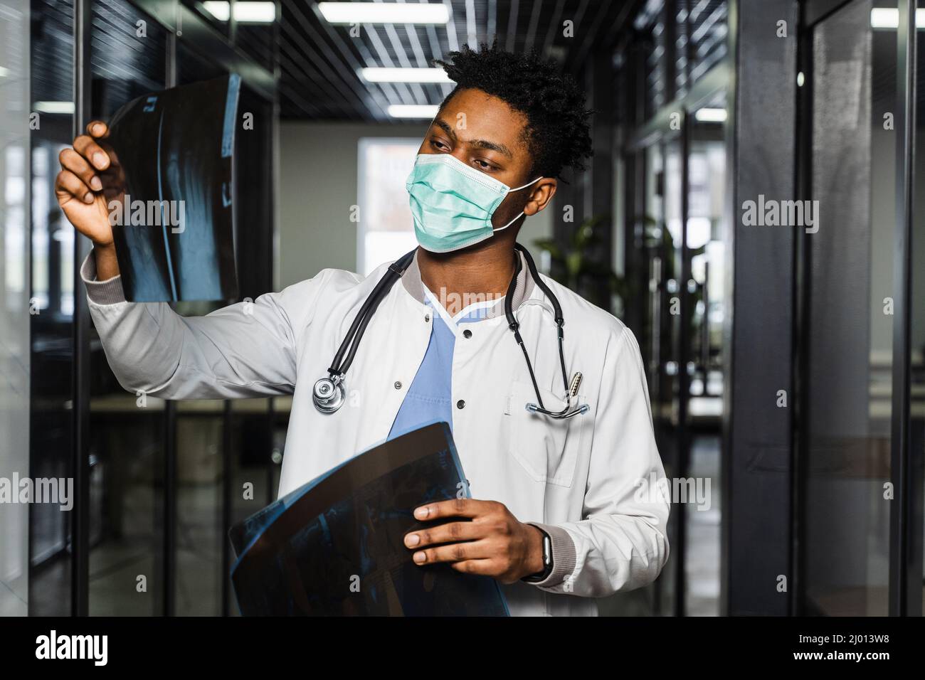 African doctor examines x-rays in a medical clinic. Black student in ...