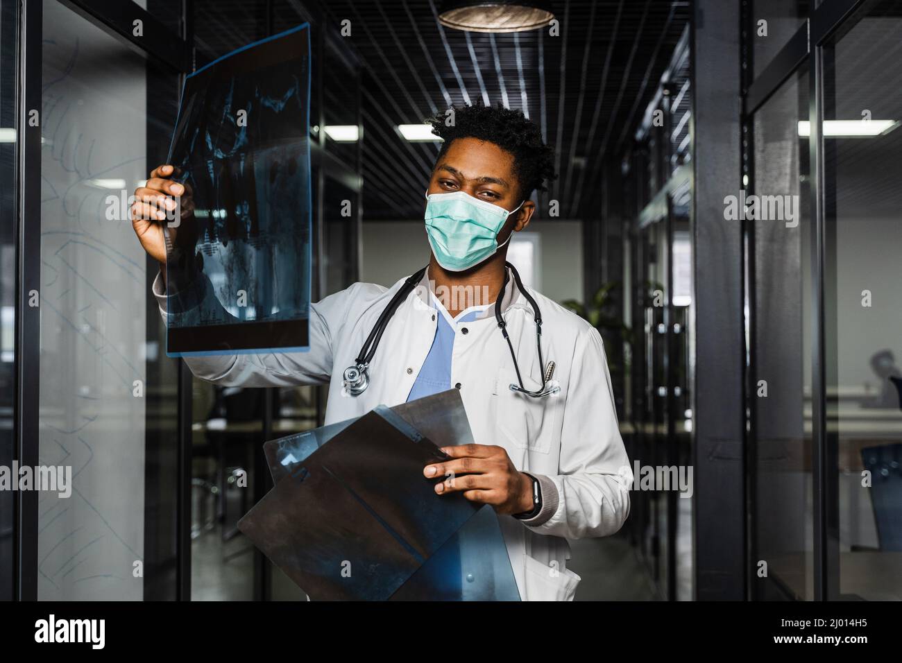 African doctor examines x-rays in a medical clinic. Black student in ...
