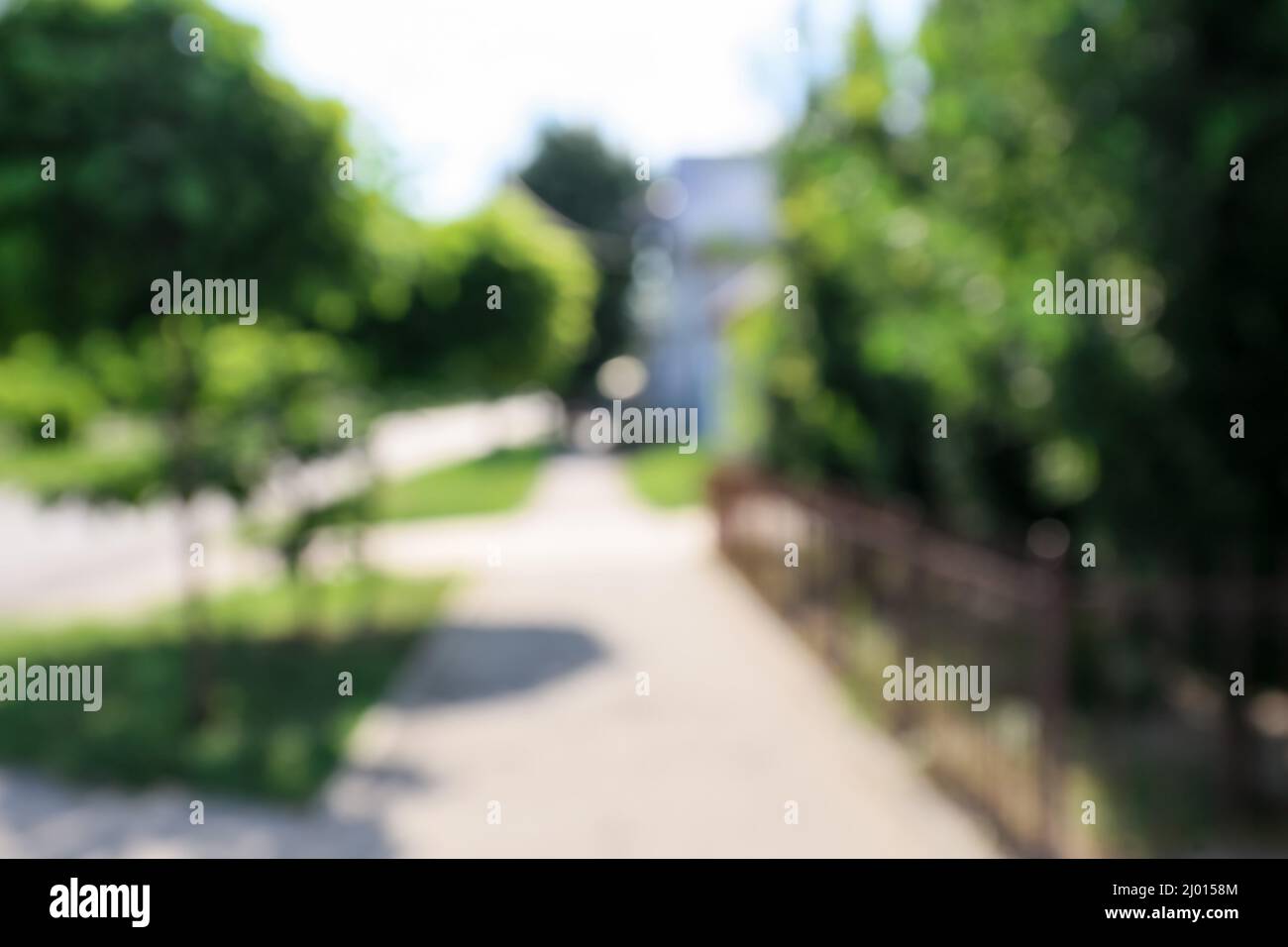 Blurred view of green trees and pathway Stock Photo - Alamy