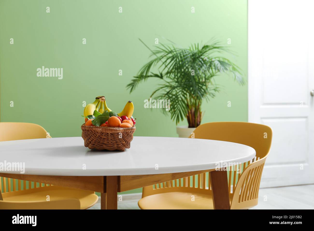 Wicker fruit basket on dining table in room Stock Photo - Alamy