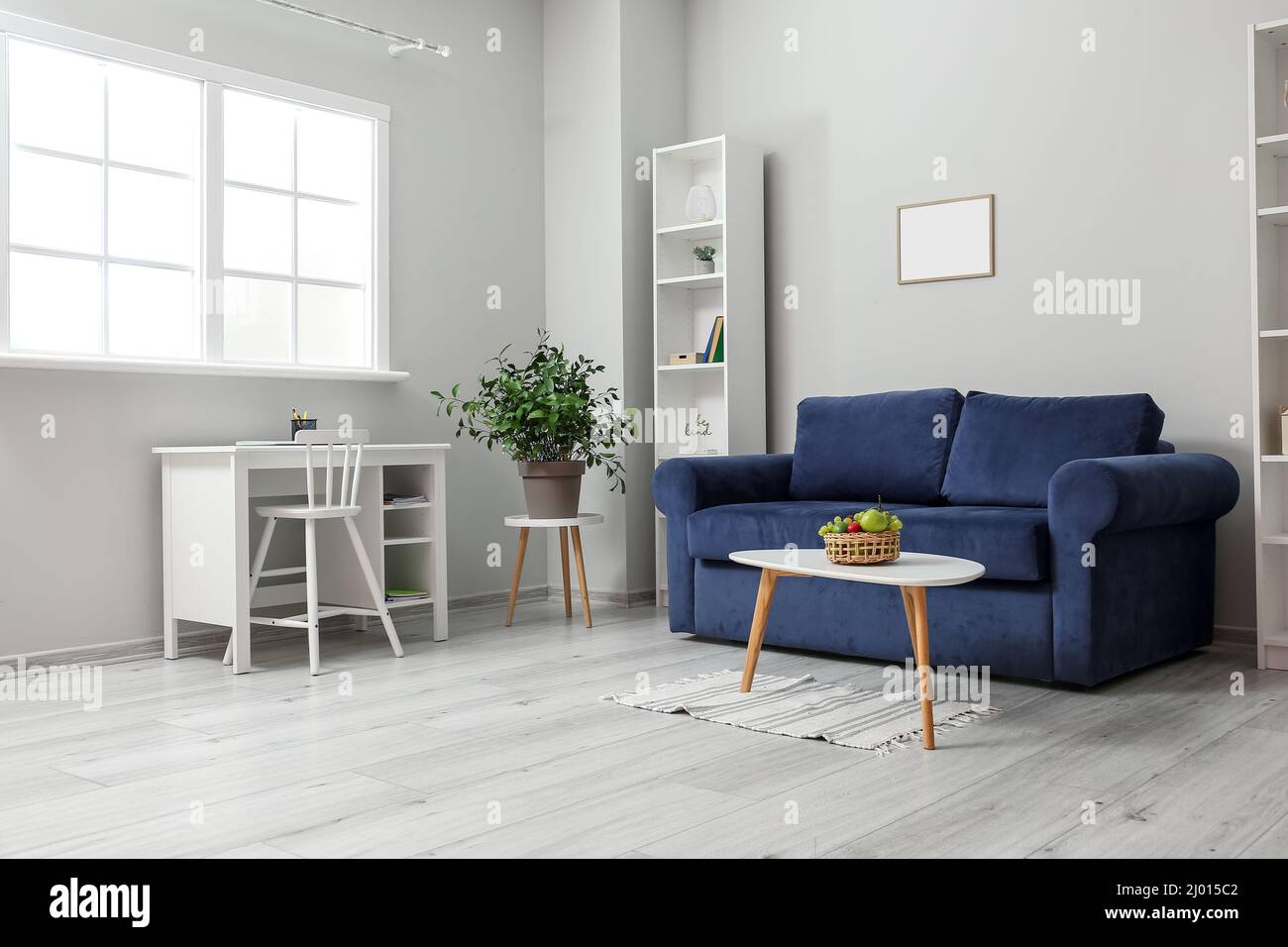 Interior of light living room with blue sofa, table and fruit basket ...