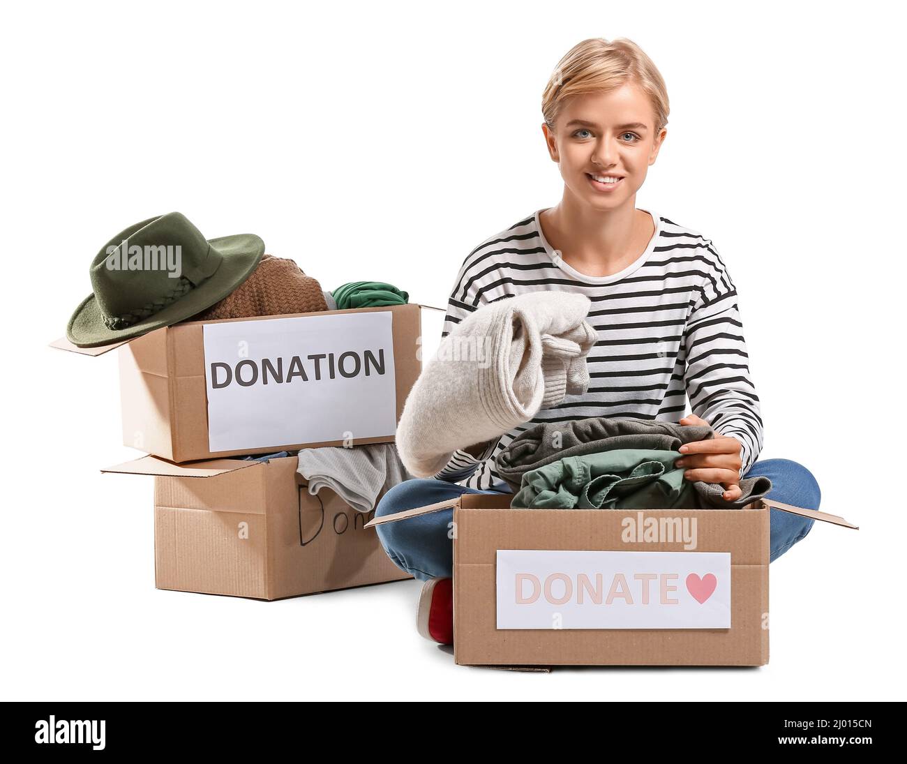 Young woman putting clothes in box for donation on white background ...