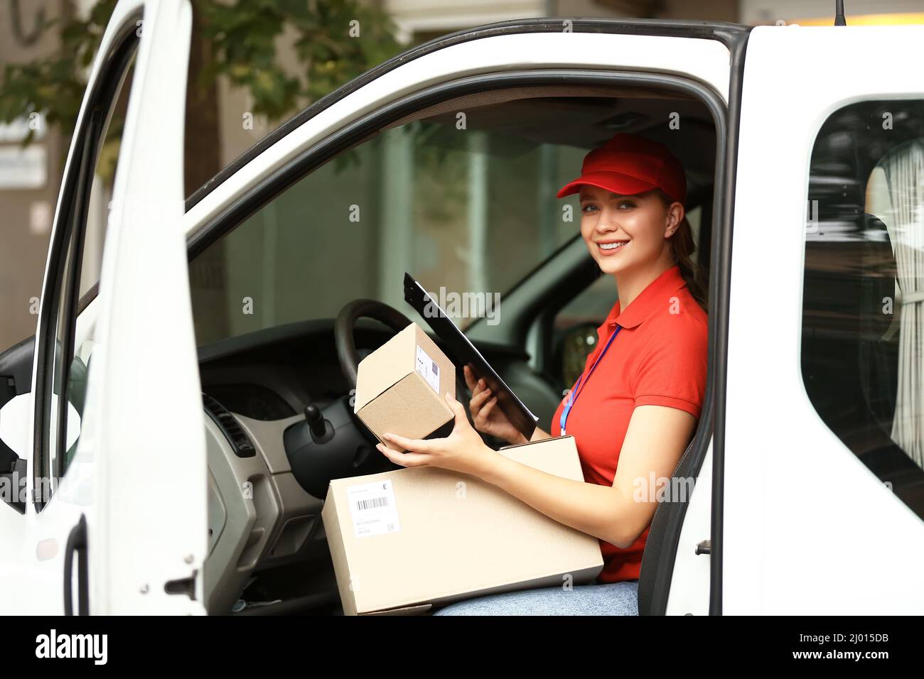 Female courier of delivery company with parcels in car Stock Photo - Alamy