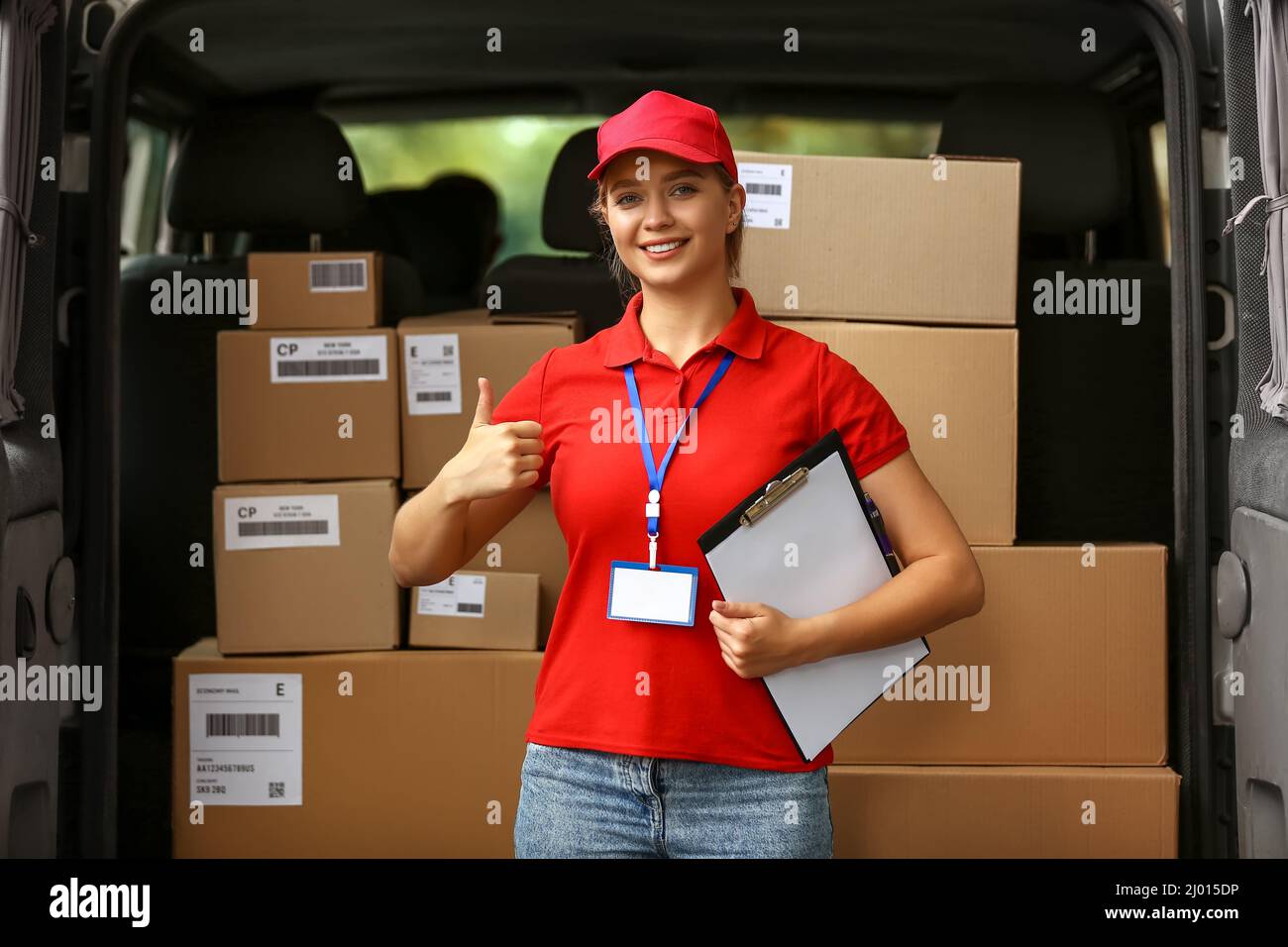 Female courier of delivery company showing thumb-up near automobile ...