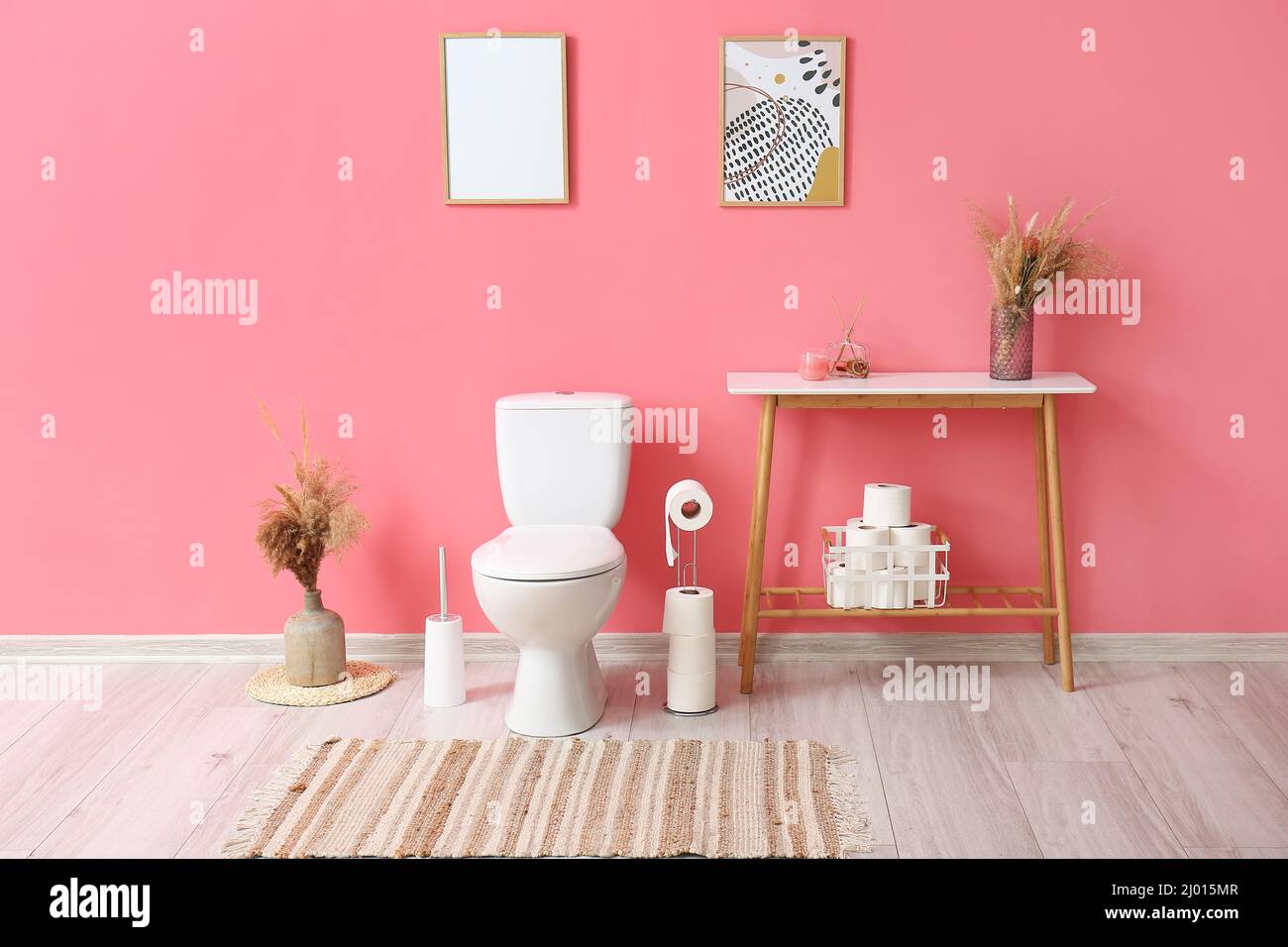 Interior of stylish restroom with toilet bowl, table and paper rolls ...