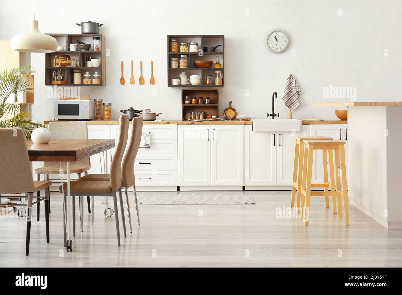 Interior of light modern kitchen with white counters and dining table ...