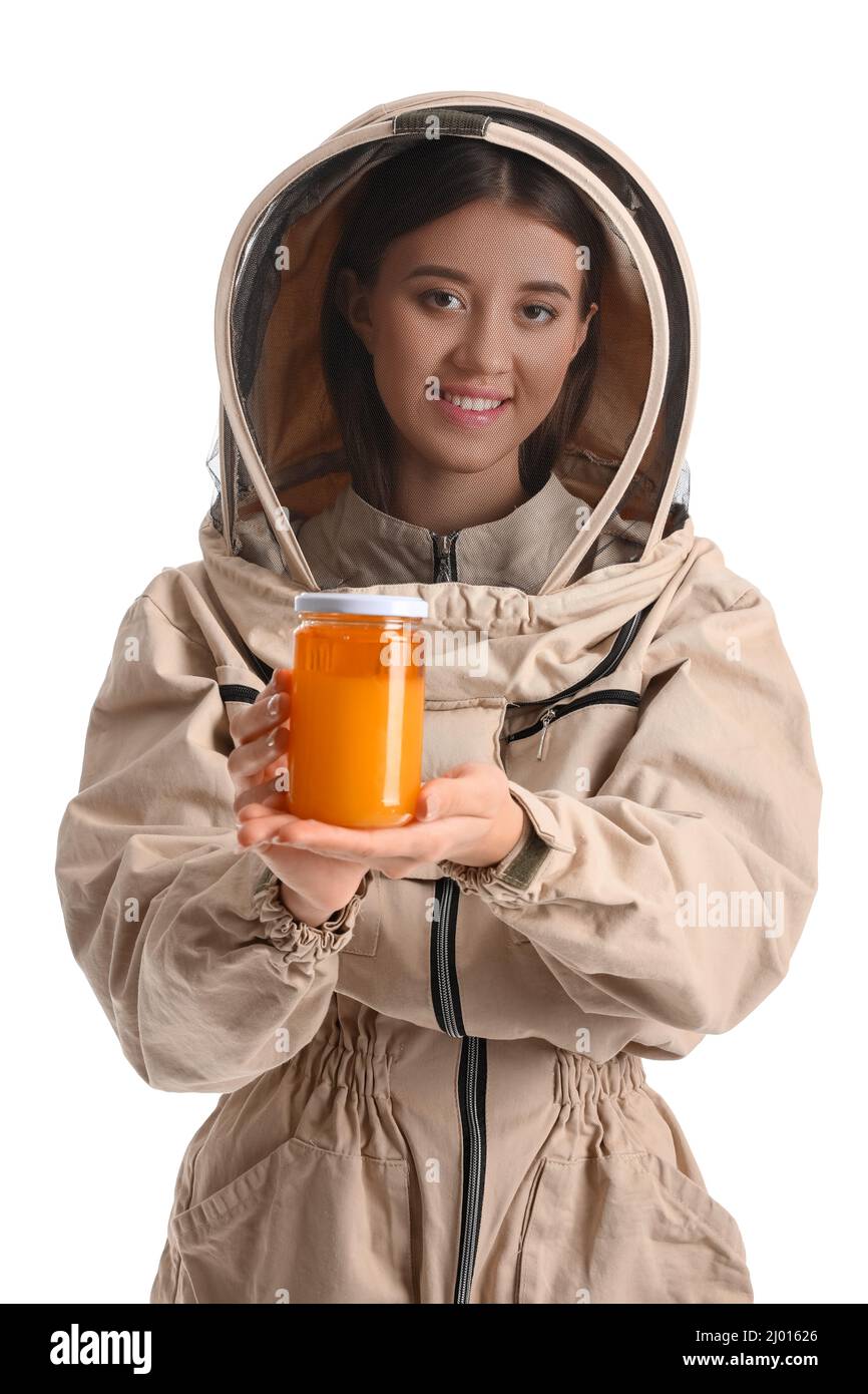 Female beekeeper in protective suit with jar of honey on white ...