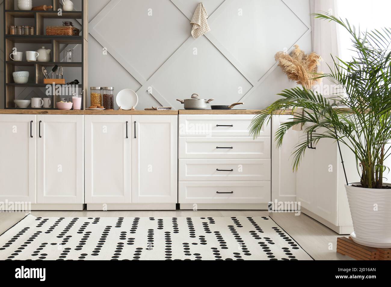 Interior of light kitchen with white counters, shelving unit and food ...
