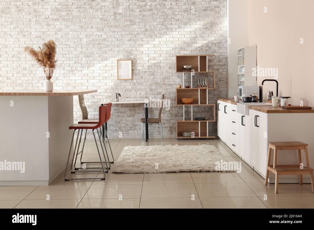 Interior of modern kitchen with white counters, shelving unit and brick ...
