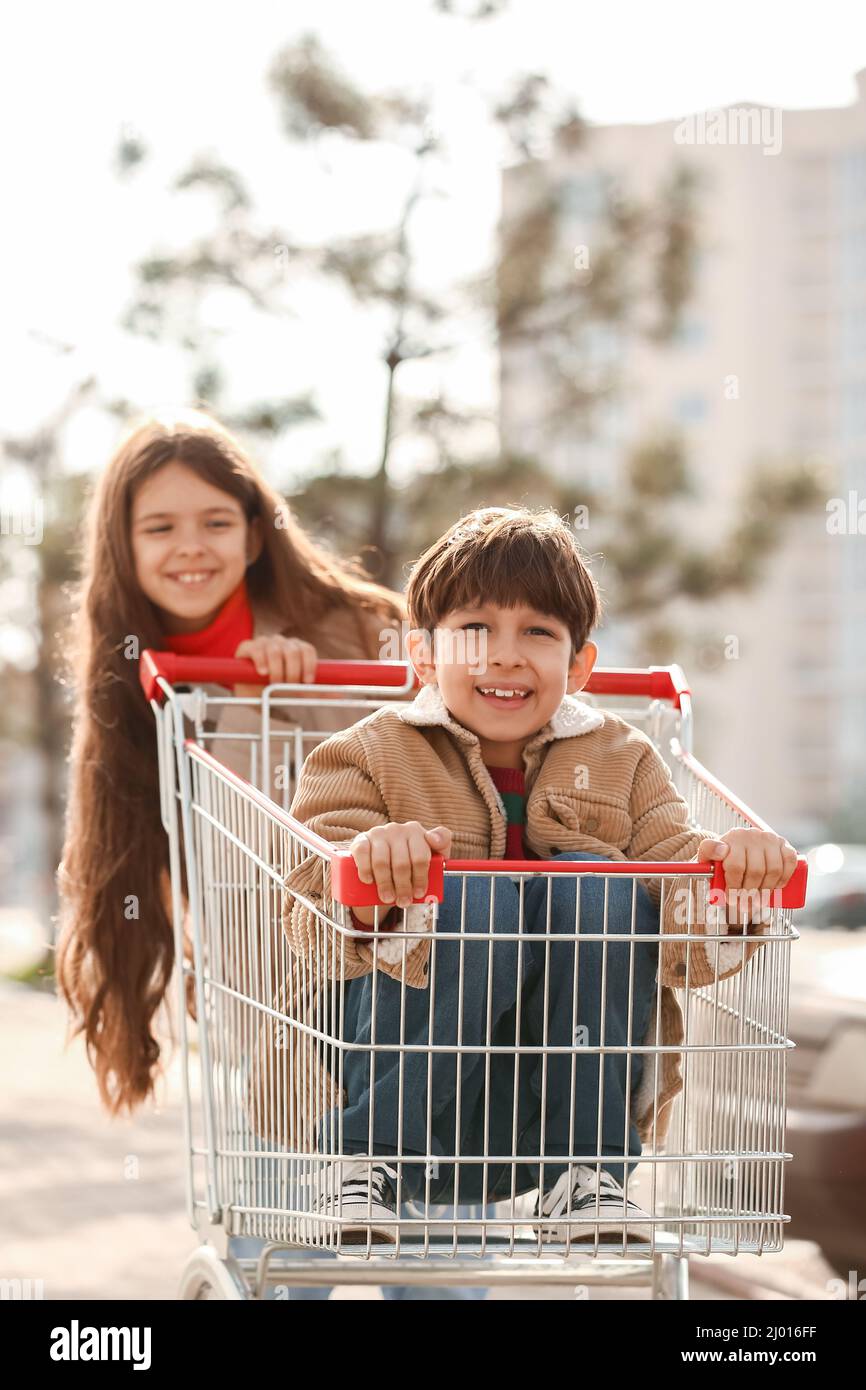 Cute children playing with shopping cart outdoors Stock Photo - Alamy