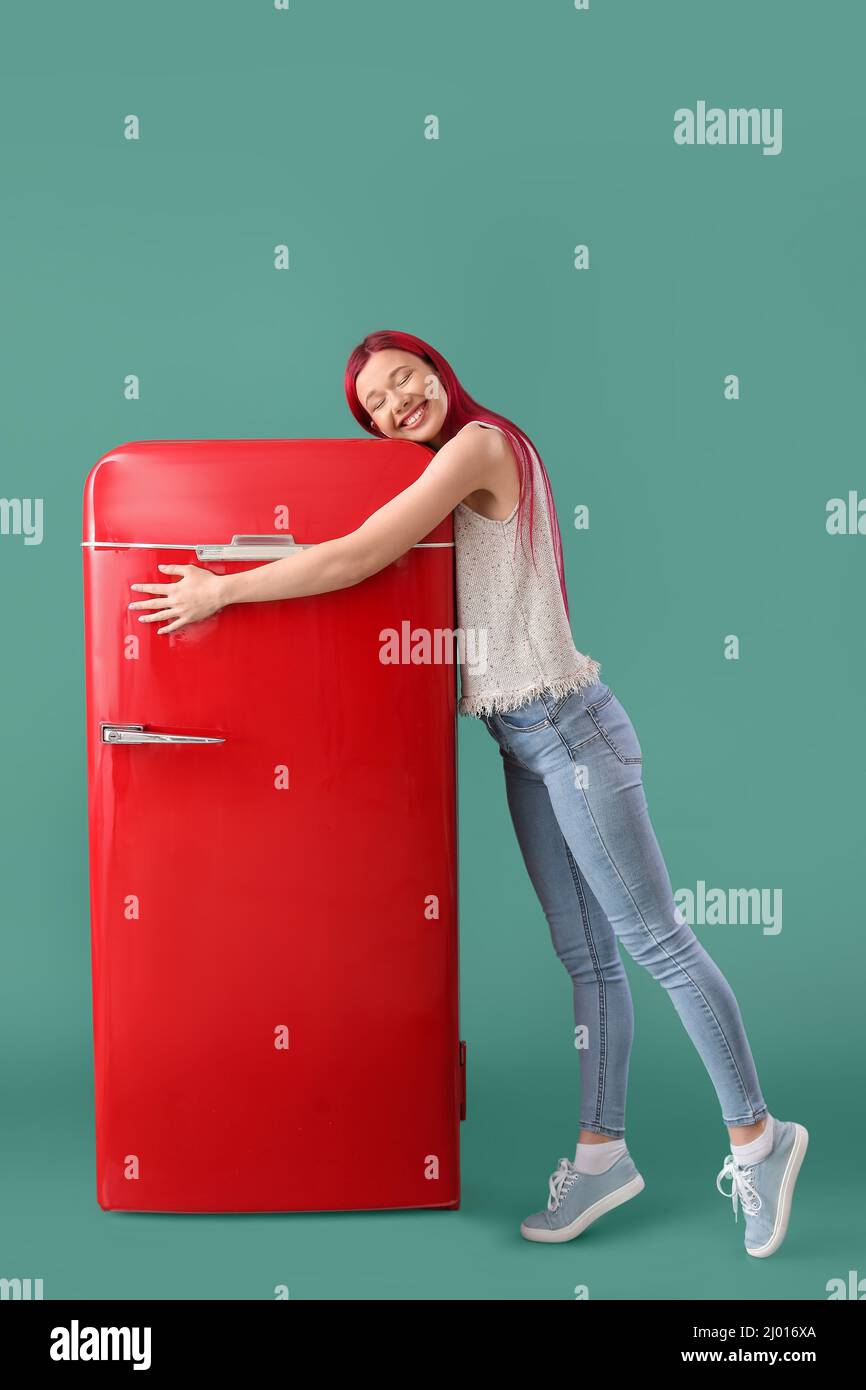 Beautiful young woman hugging red fridge on green background Stock ...