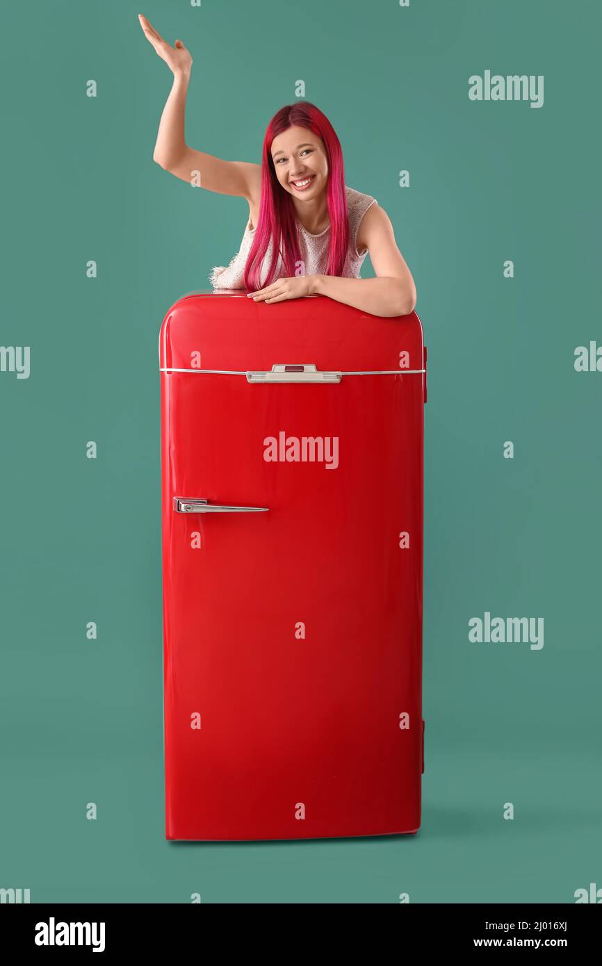 Beautiful young woman with red fridge on green background Stock Photo ...