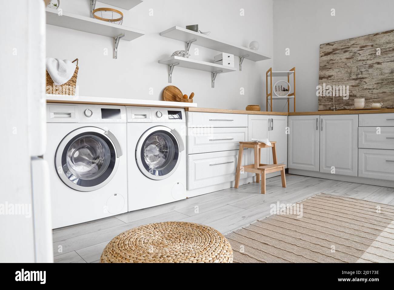 Interior of light kitchen with washing machines, laundry basket and ...