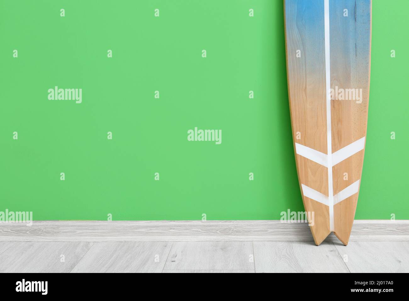 Modern surfboard near green wall in room Stock Photo - Alamy