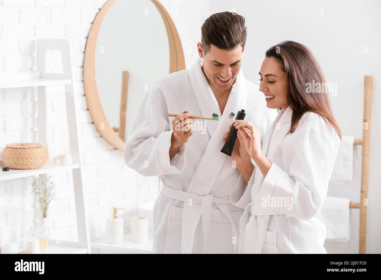 Young couple brushing teeth with activated charcoal tooth paste in ...