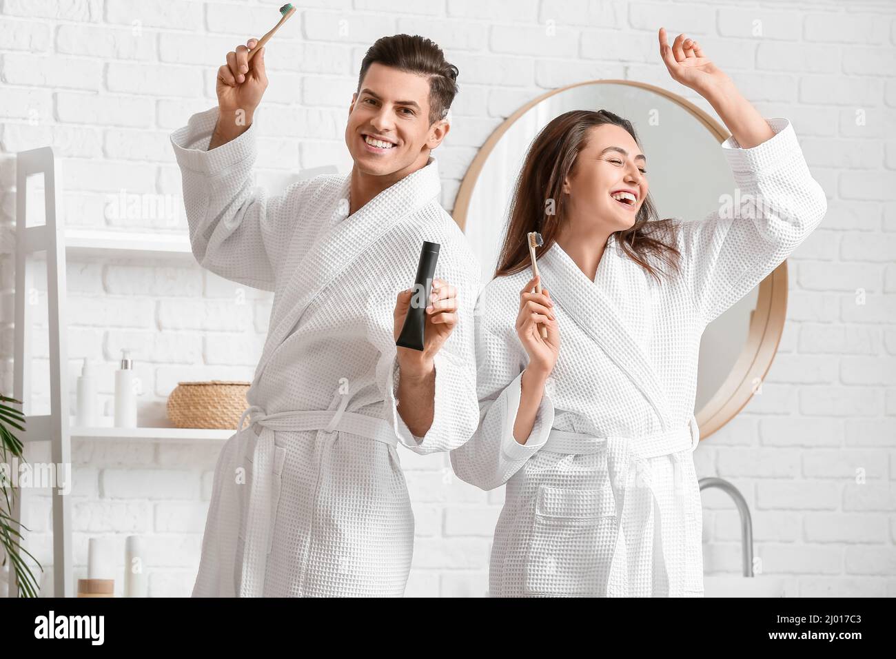 Young couple having fun while brushing teeth with activated charcoal ...