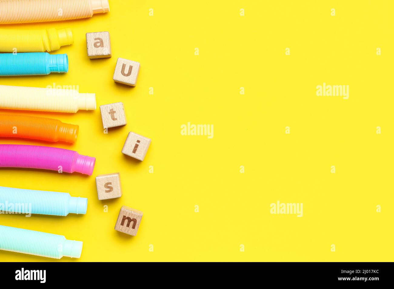 Wooden cubes with word AUTISM and Pop Tubes on yellow background Stock ...