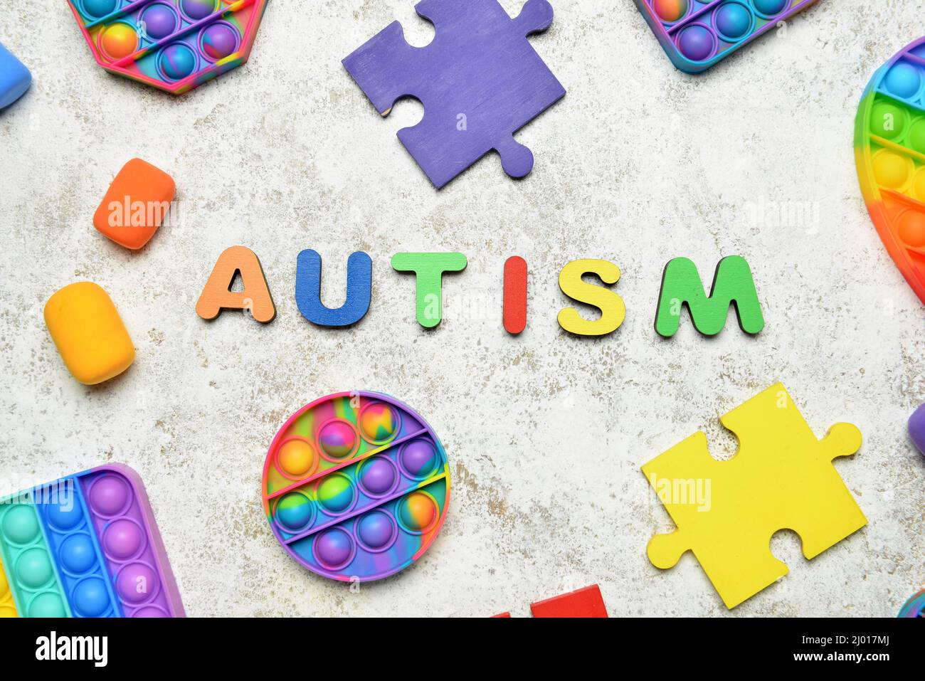 Word AUTISM with toys, plasticine and puzzle pieces on light background ...