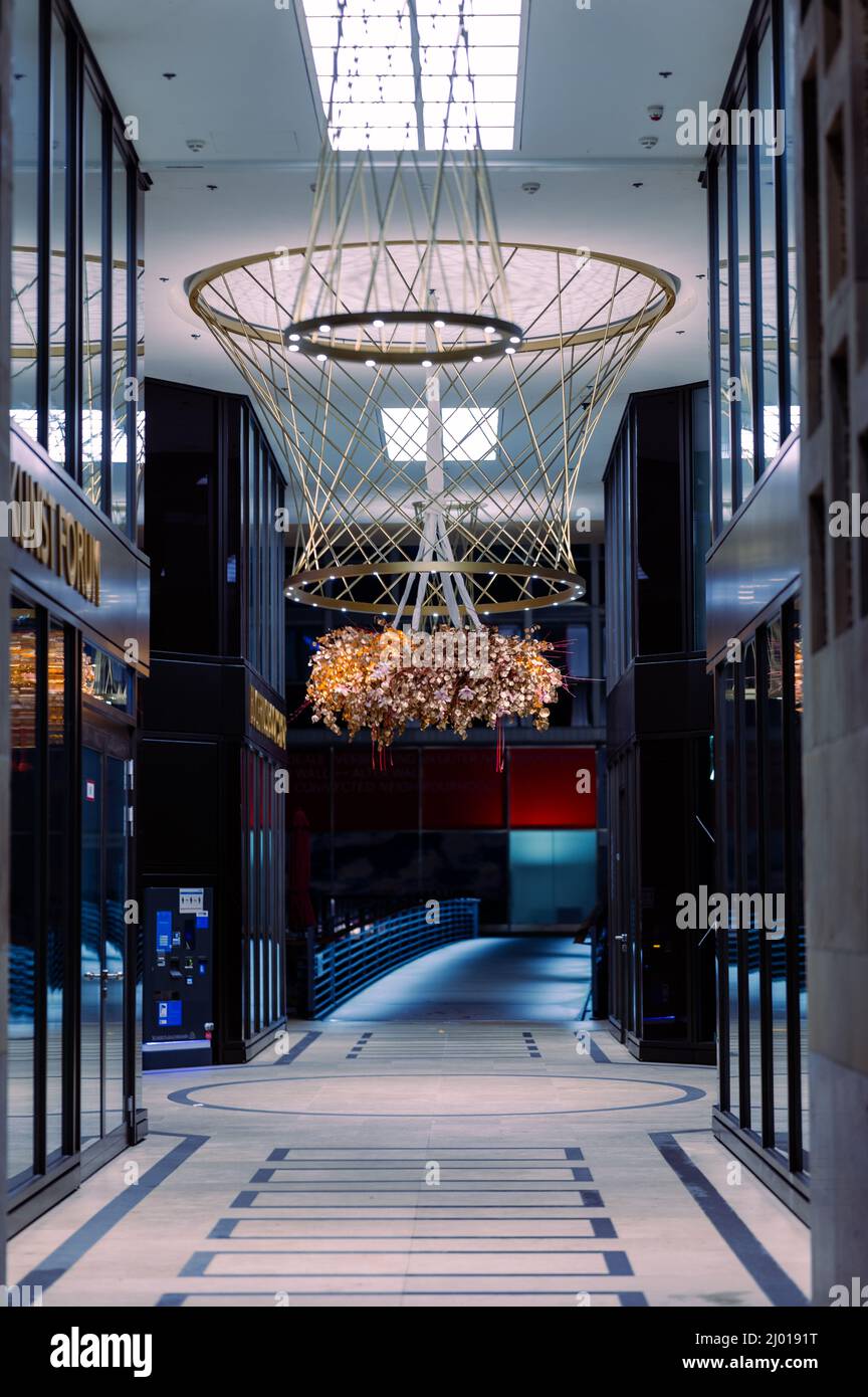 A modern chandelier shaped like a basketball hoop in a middle of a hall ...