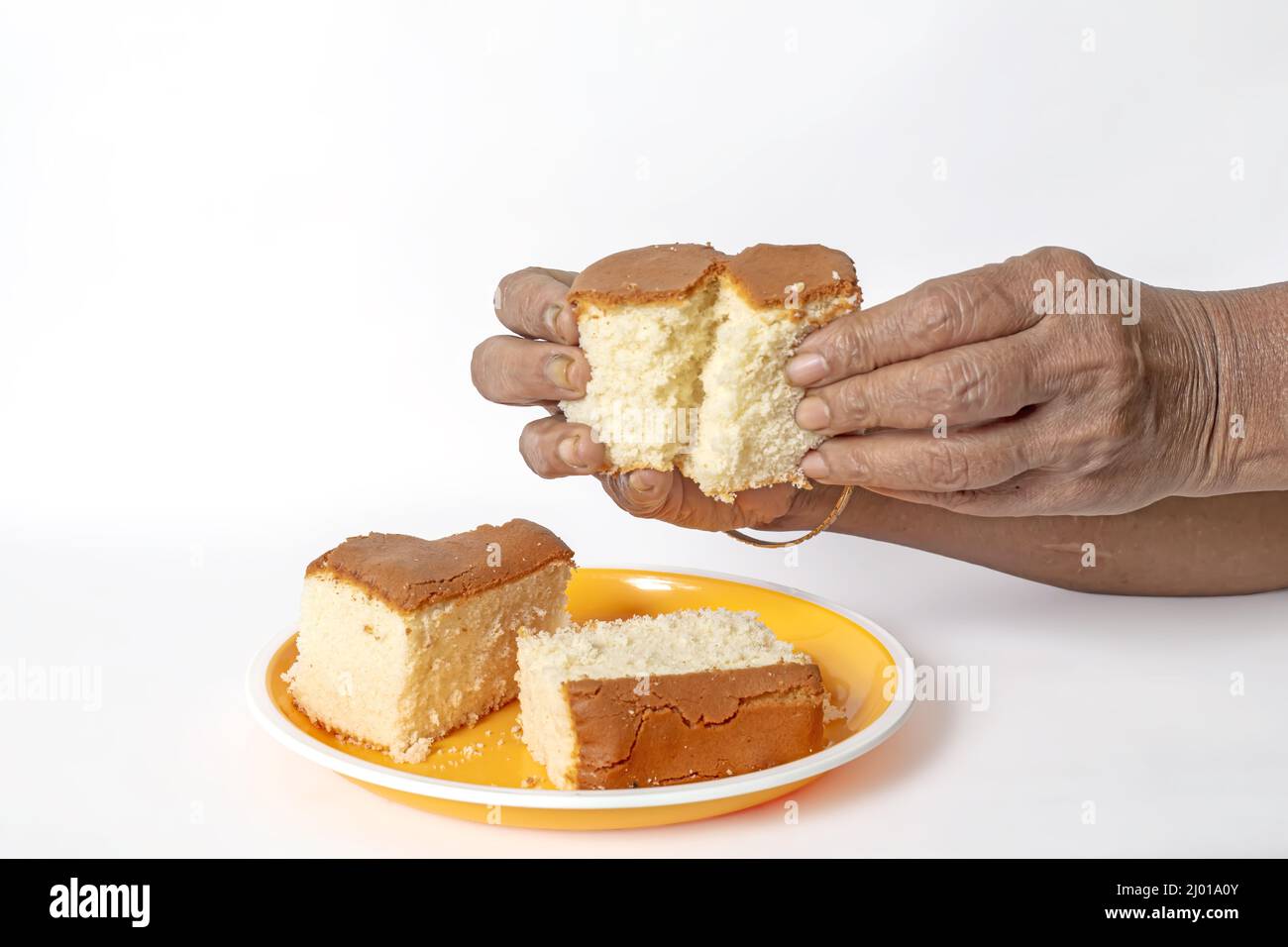 Close-up shot of human hands splitting a peace of homemade sponge cake ...