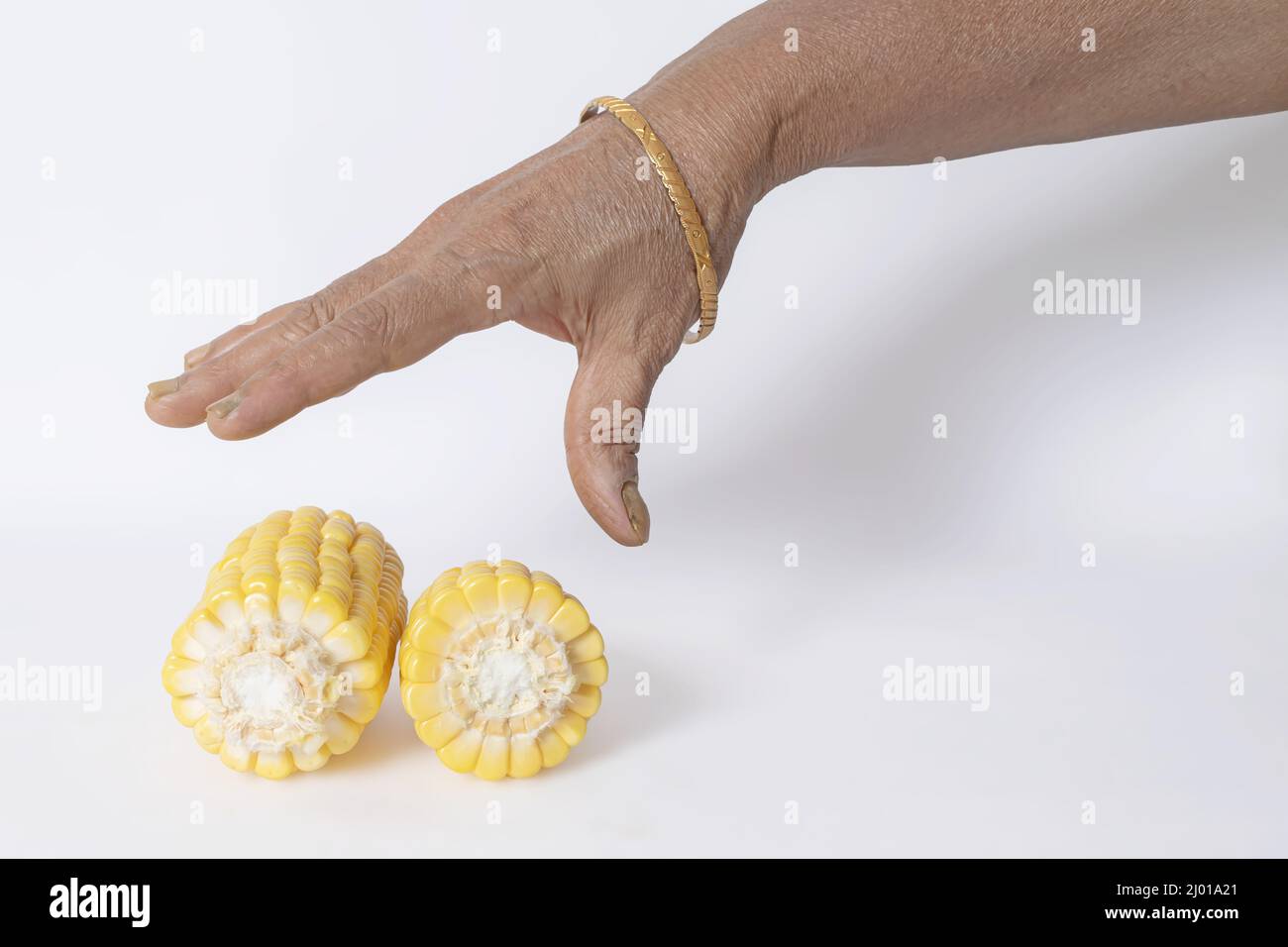 Close-up shot of a hand on a top of cut corn cob isolated on a white ...