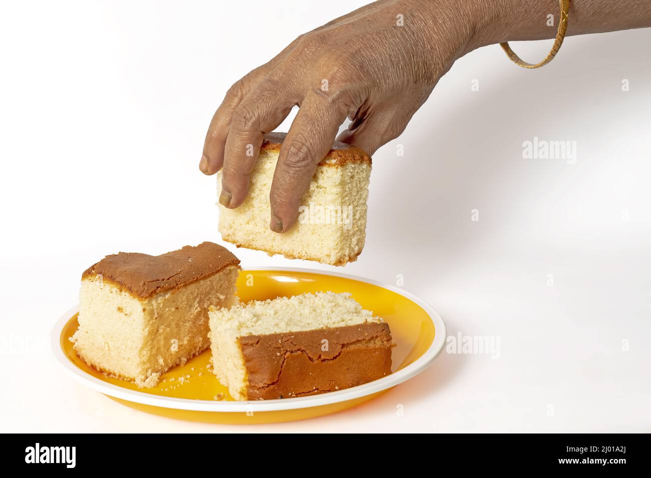 Close-up shot of a hand holding a peace of homemade sponge cake ...