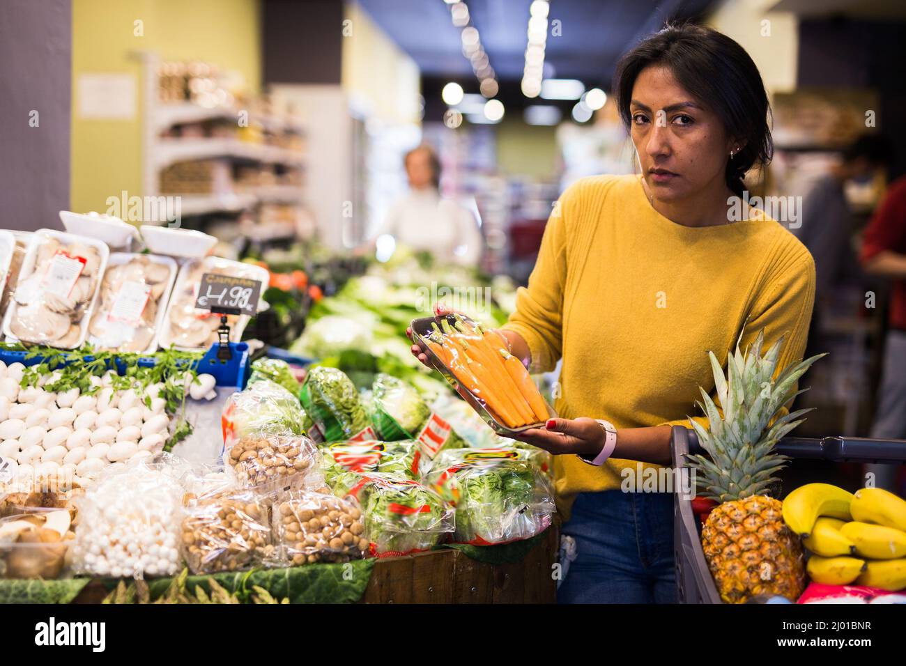 Interested hispanic woman choosing fresh carrots in supermarket Stock ...