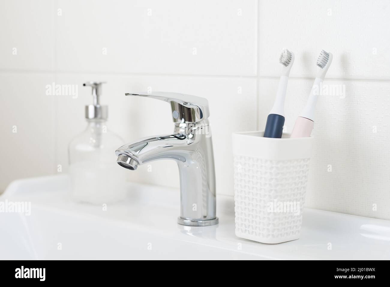 New modern ultrasonic toothbrushes in a glass on the bathroom sink. Jaw ...