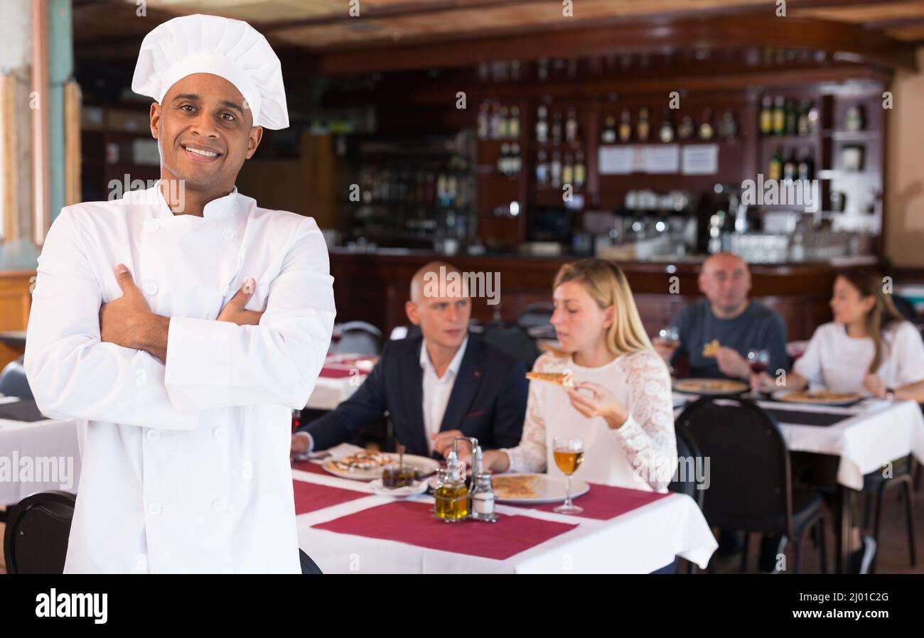 Portrait of positive chef against the background of dining guests in ...