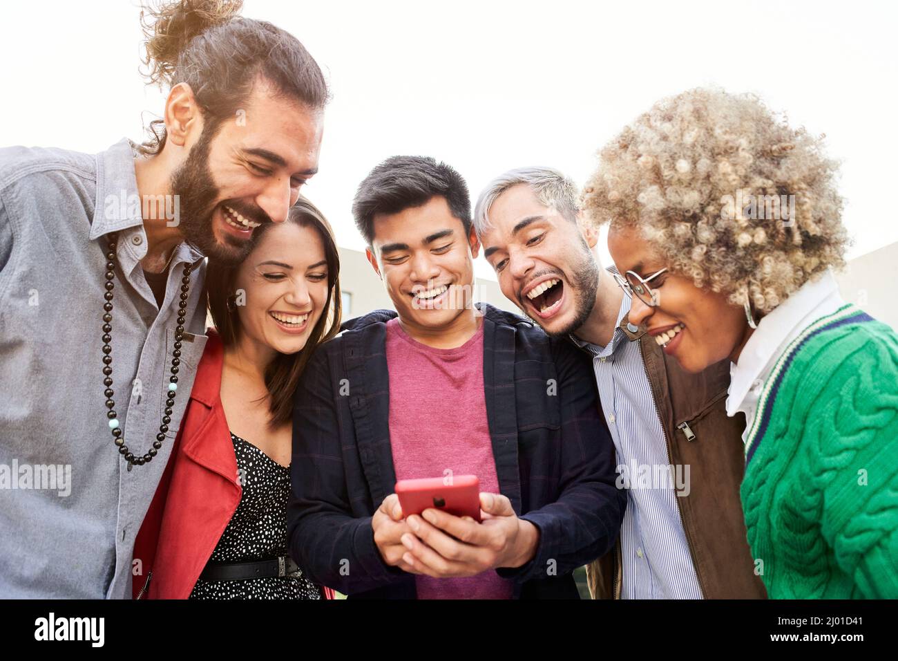 Group of smiling friends together using phones. Happy people watching ...