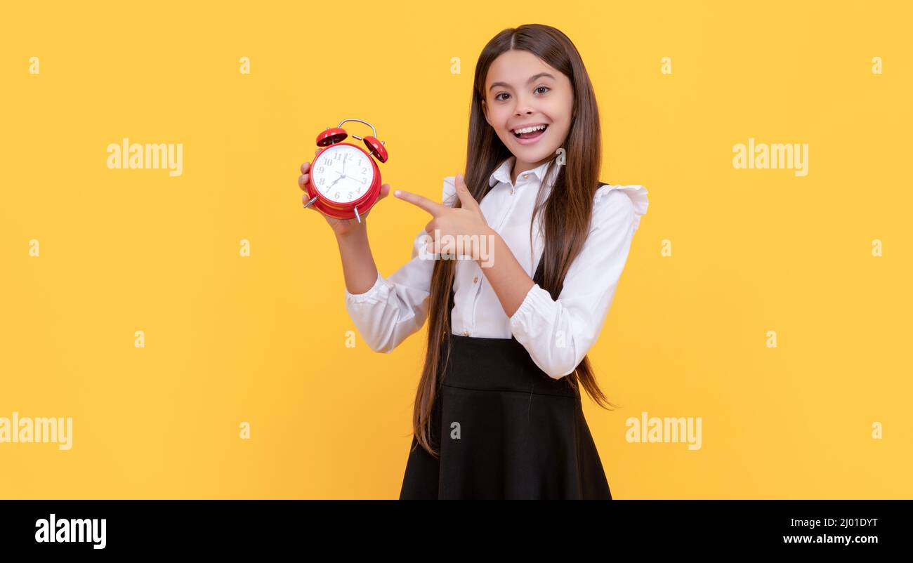 smiling child in school uniform point finger on alarm clock showing ...