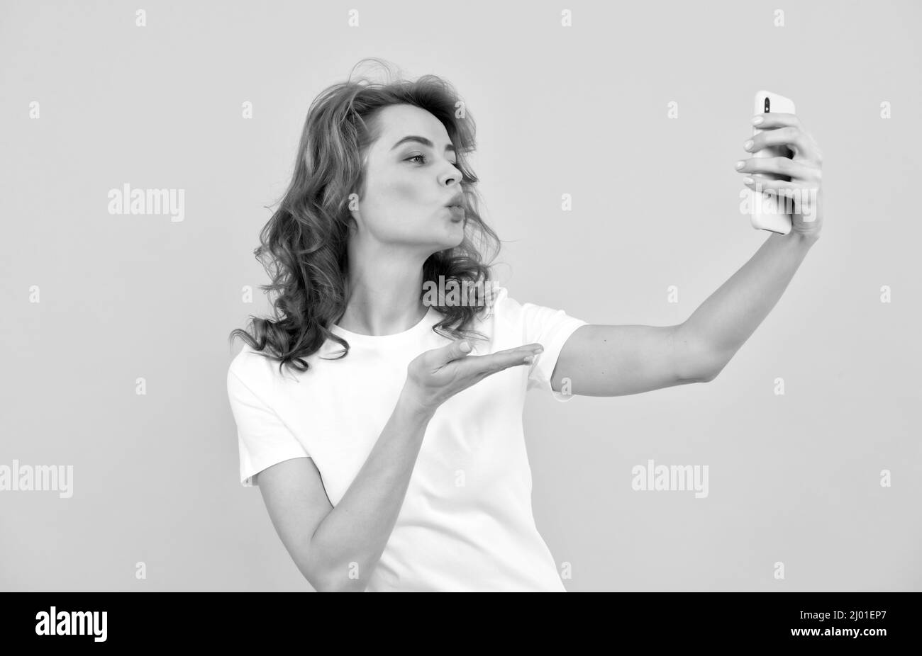 Woman make hand kissing gesture to camera mobile phone yellow ...