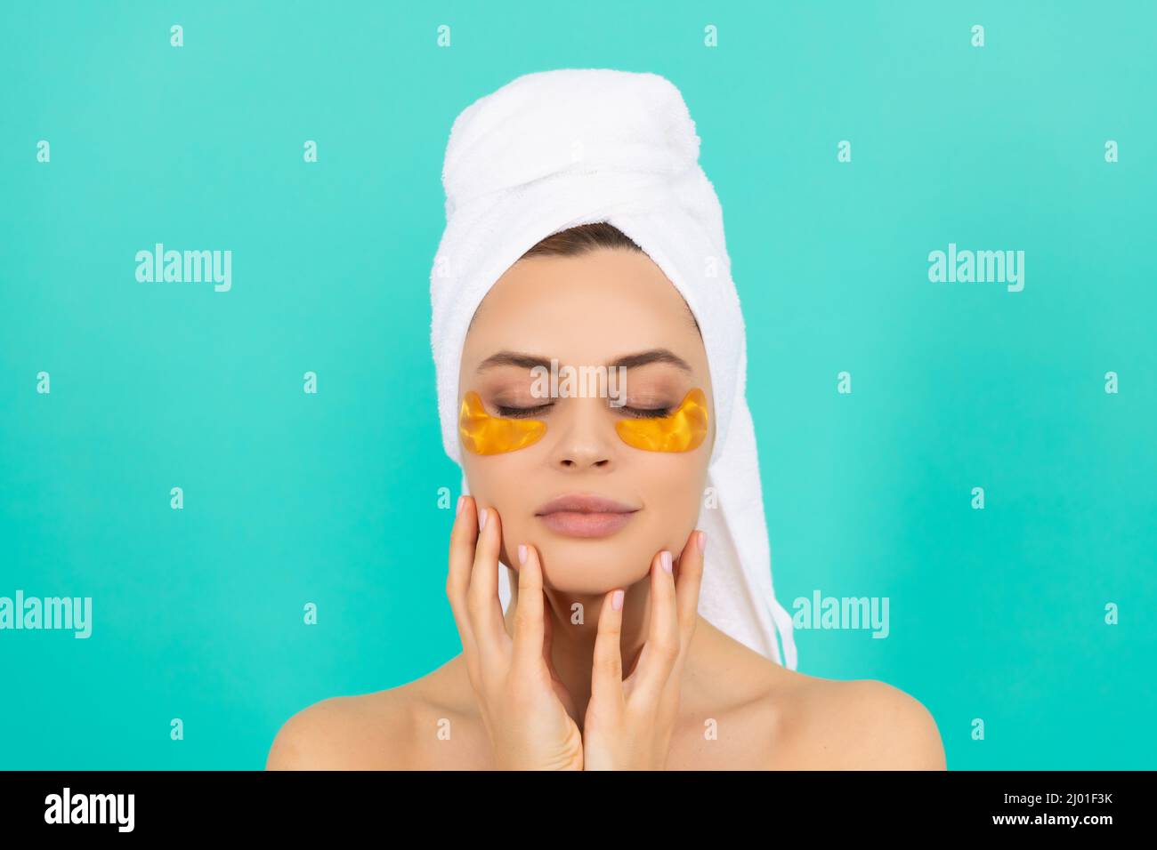 young lady has collagen golden eye patches on face with towel. closed ...