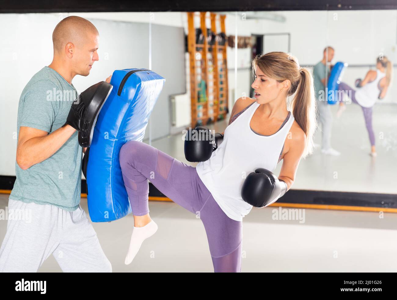 Concentrated young woman kicking boxing shield in gym Stock Photo - Alamy