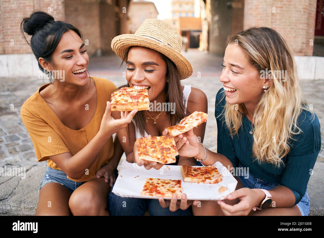 Funny group of three girls and they have fun eating pizza in the ...