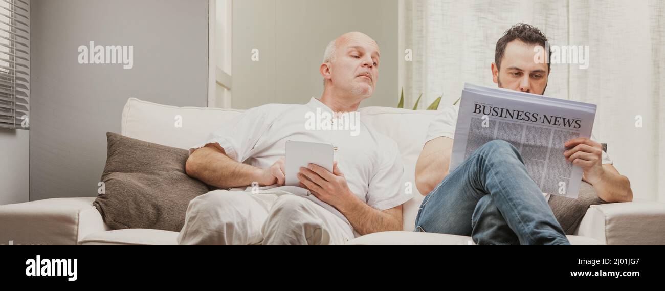 Senior man peering over the shoulder of his son or partner who is ...