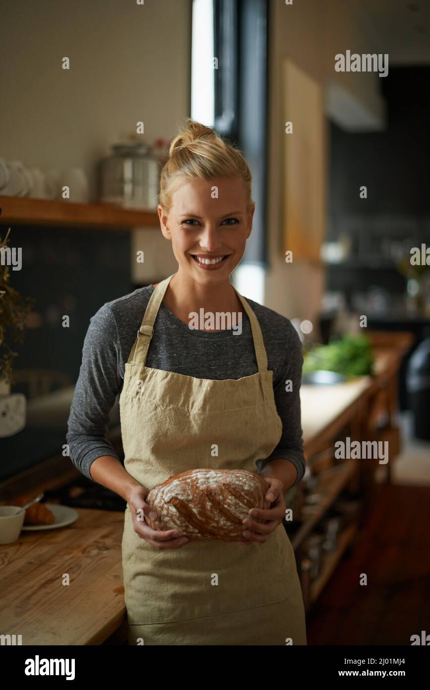 Making her own bread. Portrait of a young female baker holding homemade ...