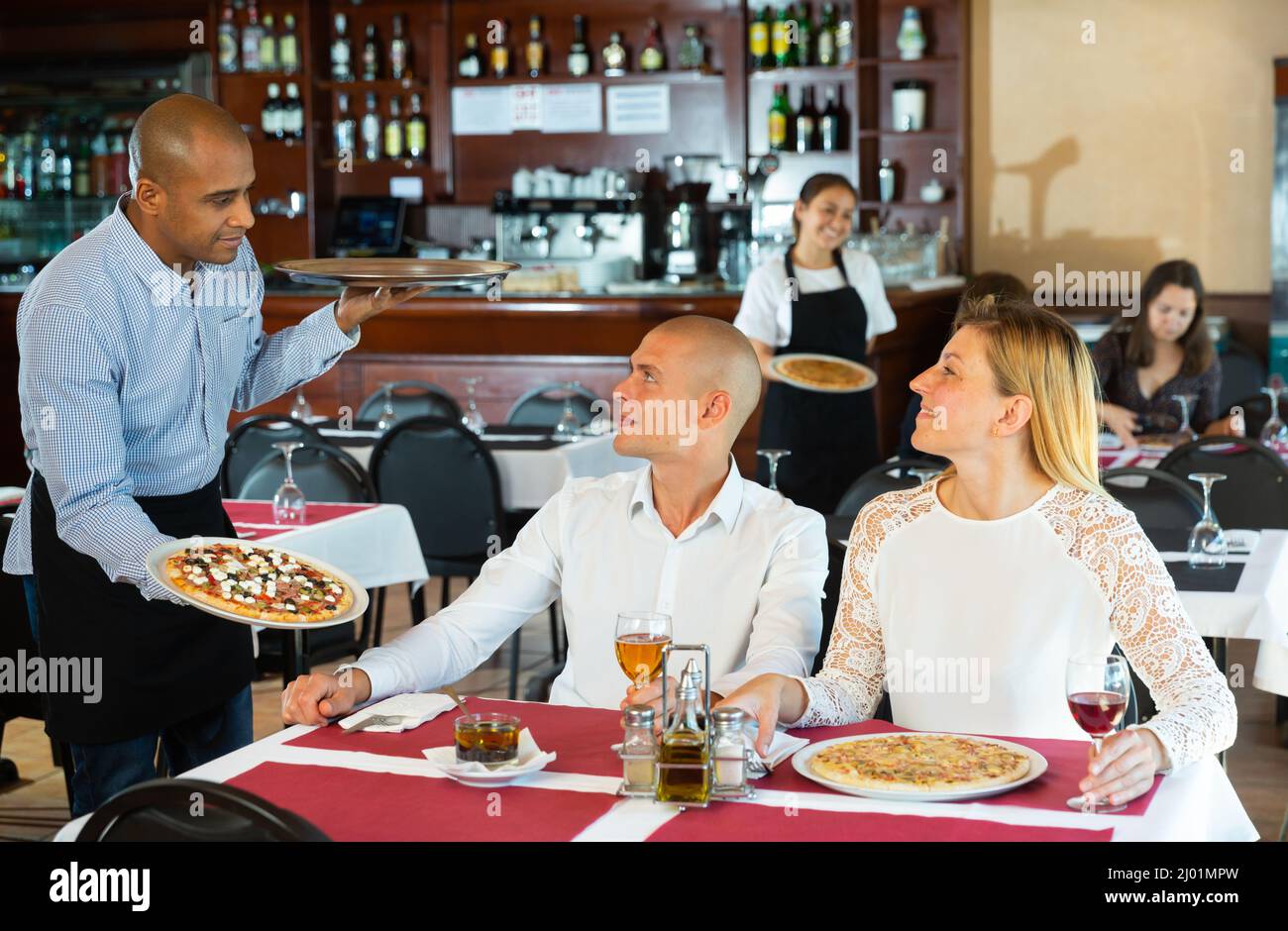 Latino waiter brought delicious pizza to restaurant guests Stock Photo ...