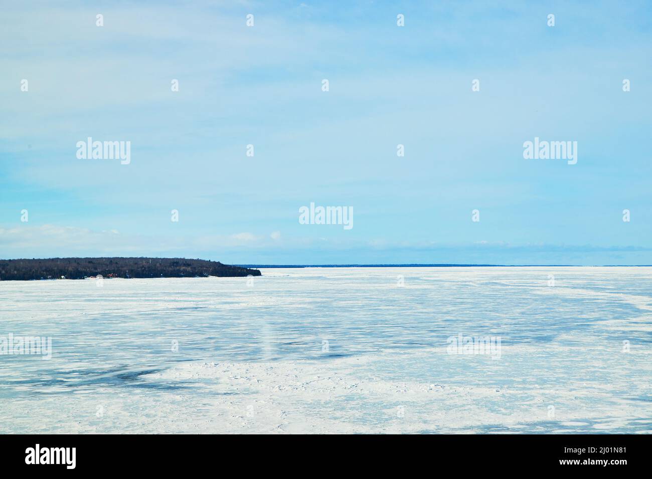 View of land from frozen lake covered in ice Stock Photo - Alamy